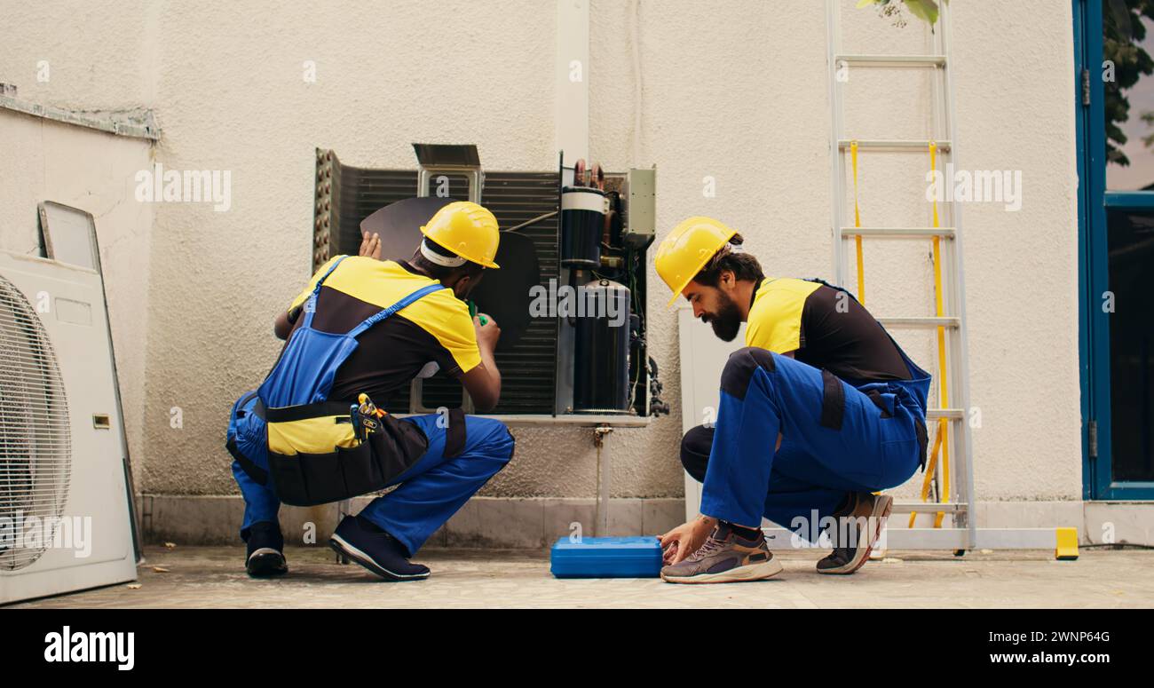 Teamworking competent mechanic opening up rusty out of service HVAC ...