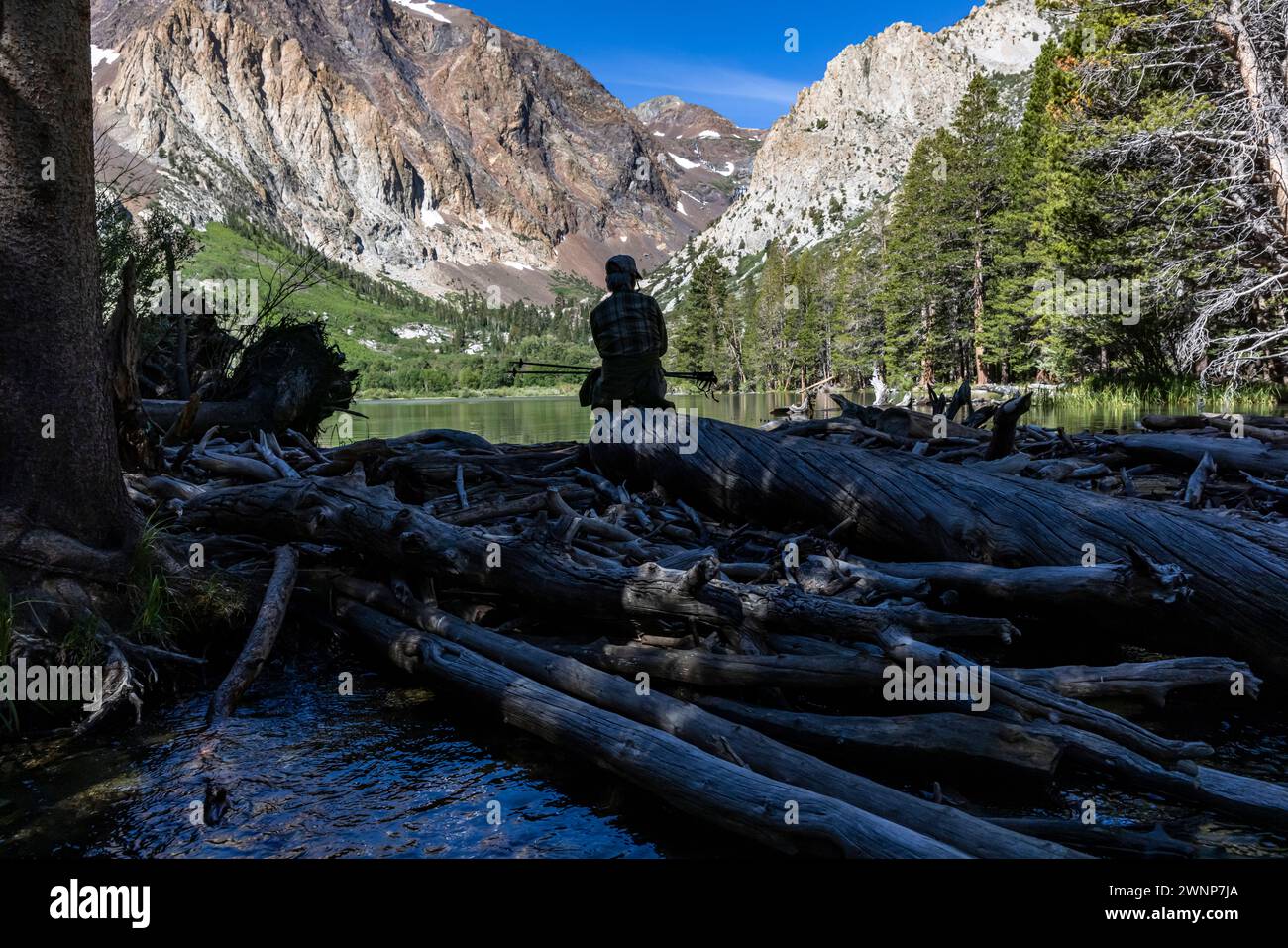 A hiker rests on the shoreline of Parker Lake to take in the view of ...