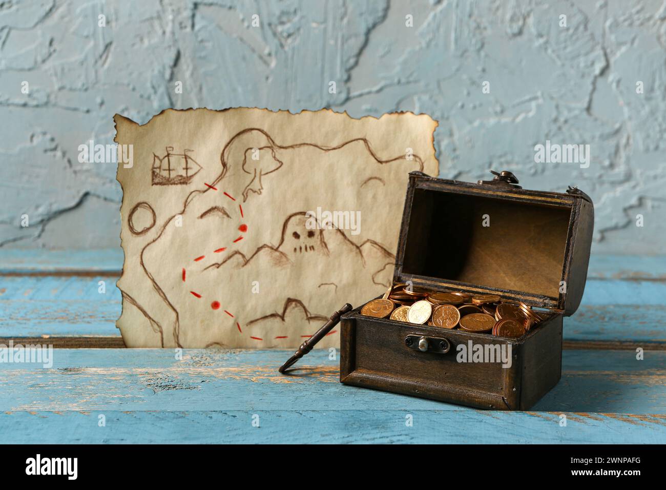 Old chest with coins, key and treasure map on blue wooden table near ...