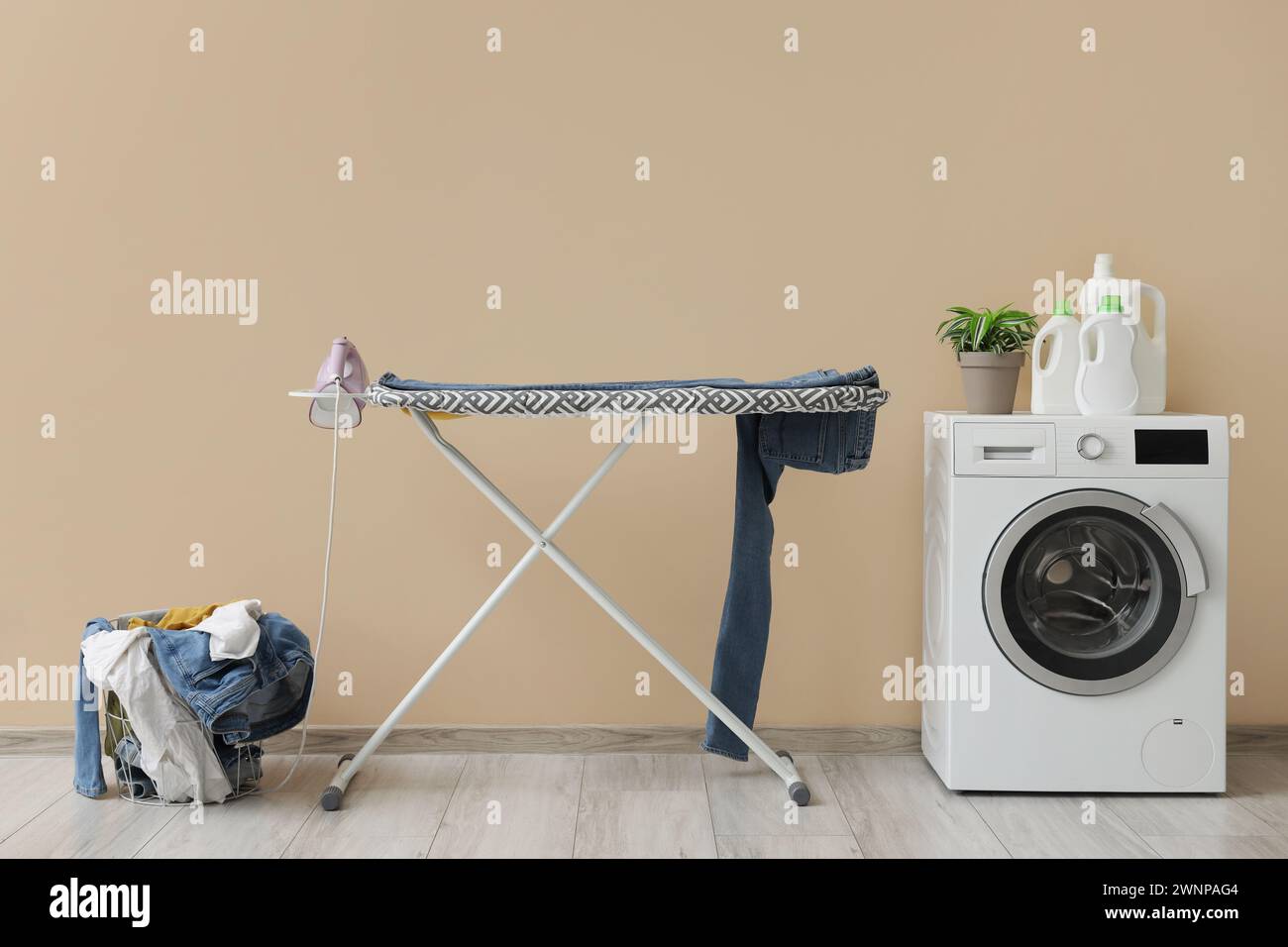 Interior of laundry room with ironing board, basket and washing machine ...