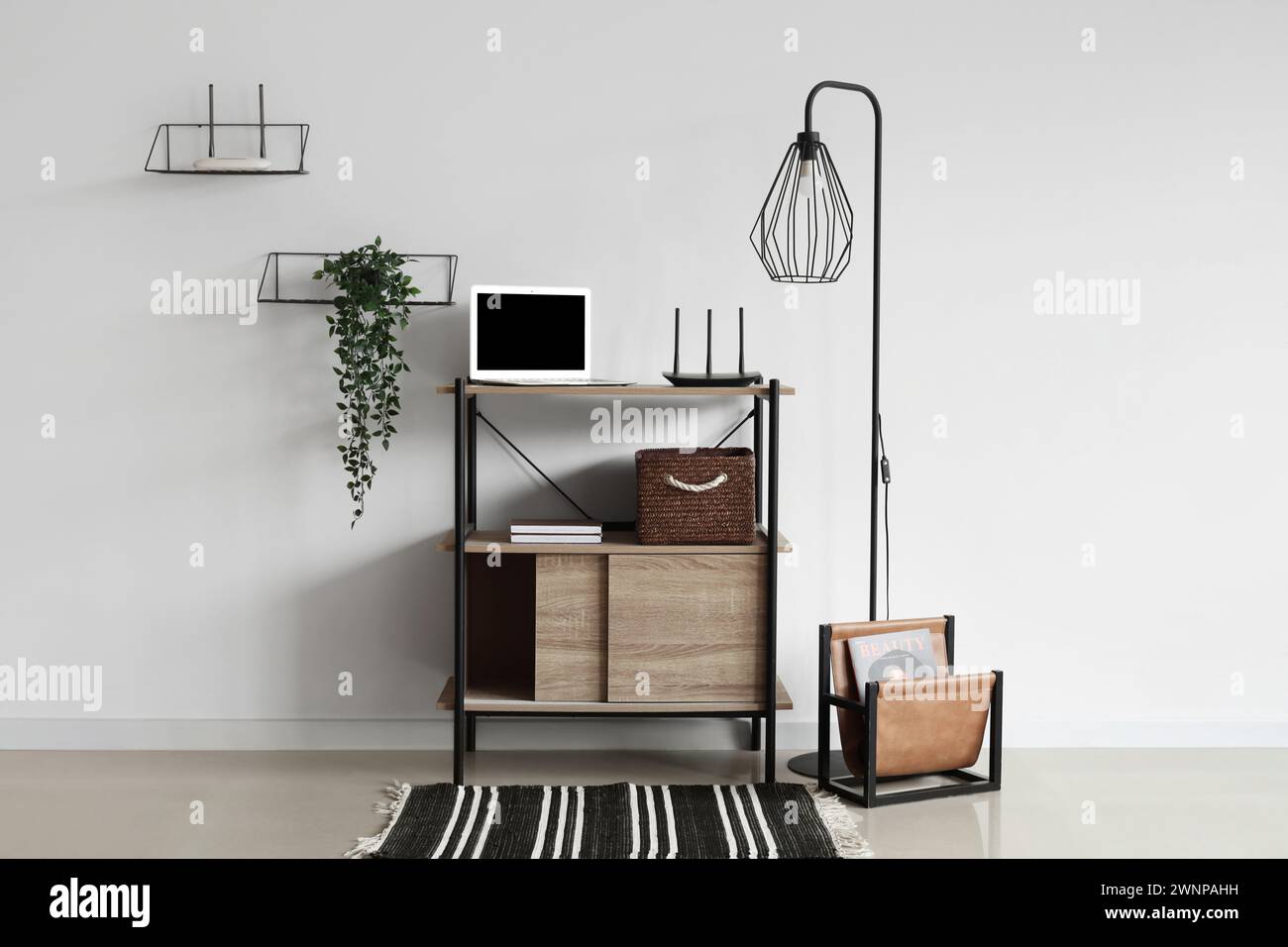 Modern wi-fi router with laptop on shelf near light wall in interior of ...