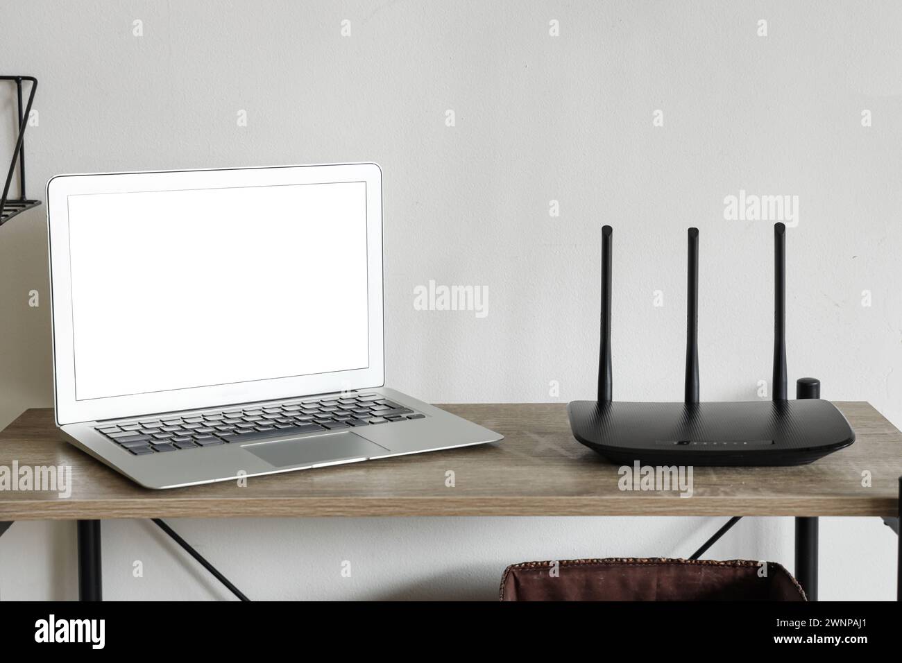 Modern wi-fi router with blank laptop on shelf near light wall Stock ...