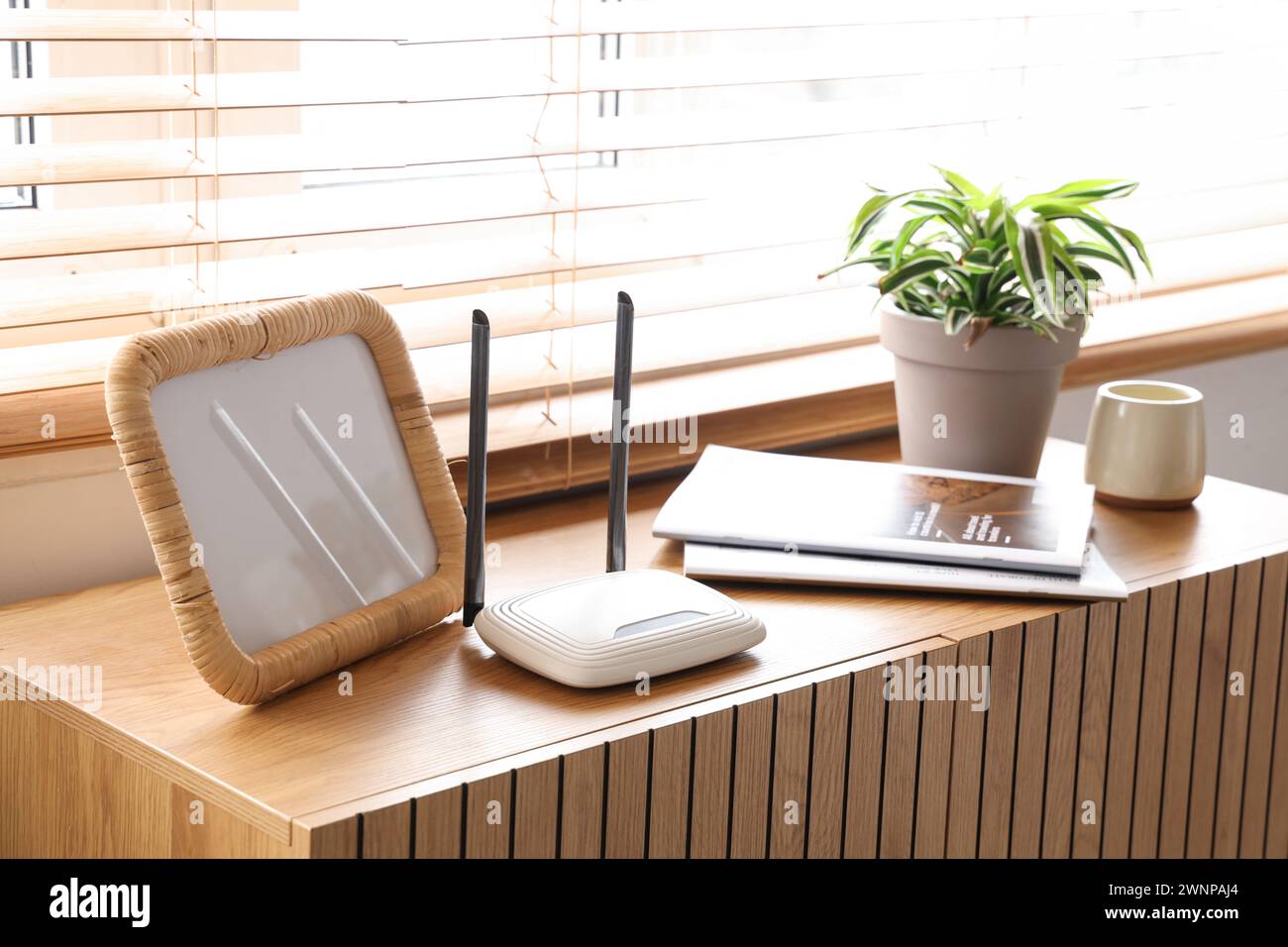 Modern wi-fi router with frame and magazines on shelf in room Stock ...