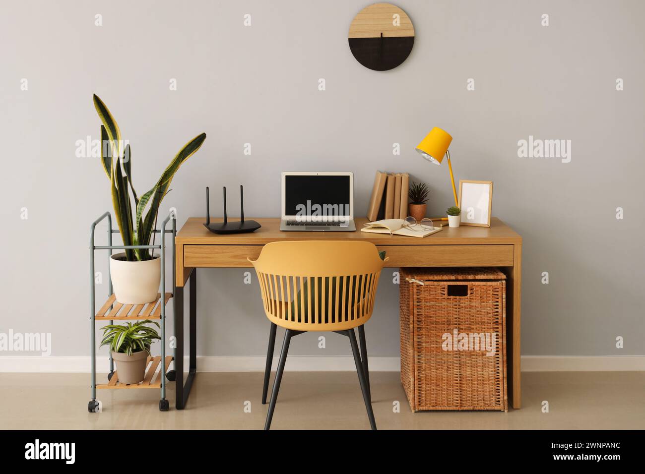 Modern workplace with wi-fi router and laptop near light wall in office ...