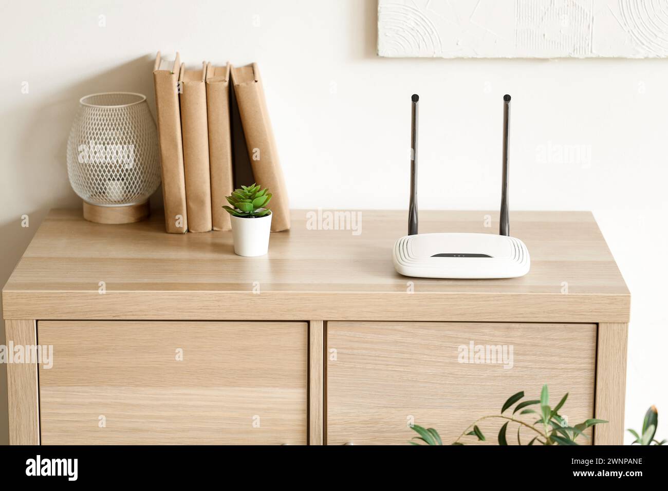 Modern wi-fi router with books, plant and lamp on commode in room Stock ...