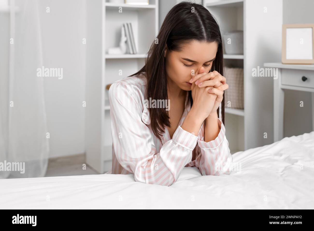 Beautiful young woman praying in bedroom at home Stock Photo - Alamy