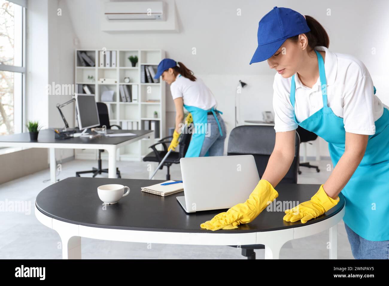Female janitor cleaning table in office Stock Photo - Alamy