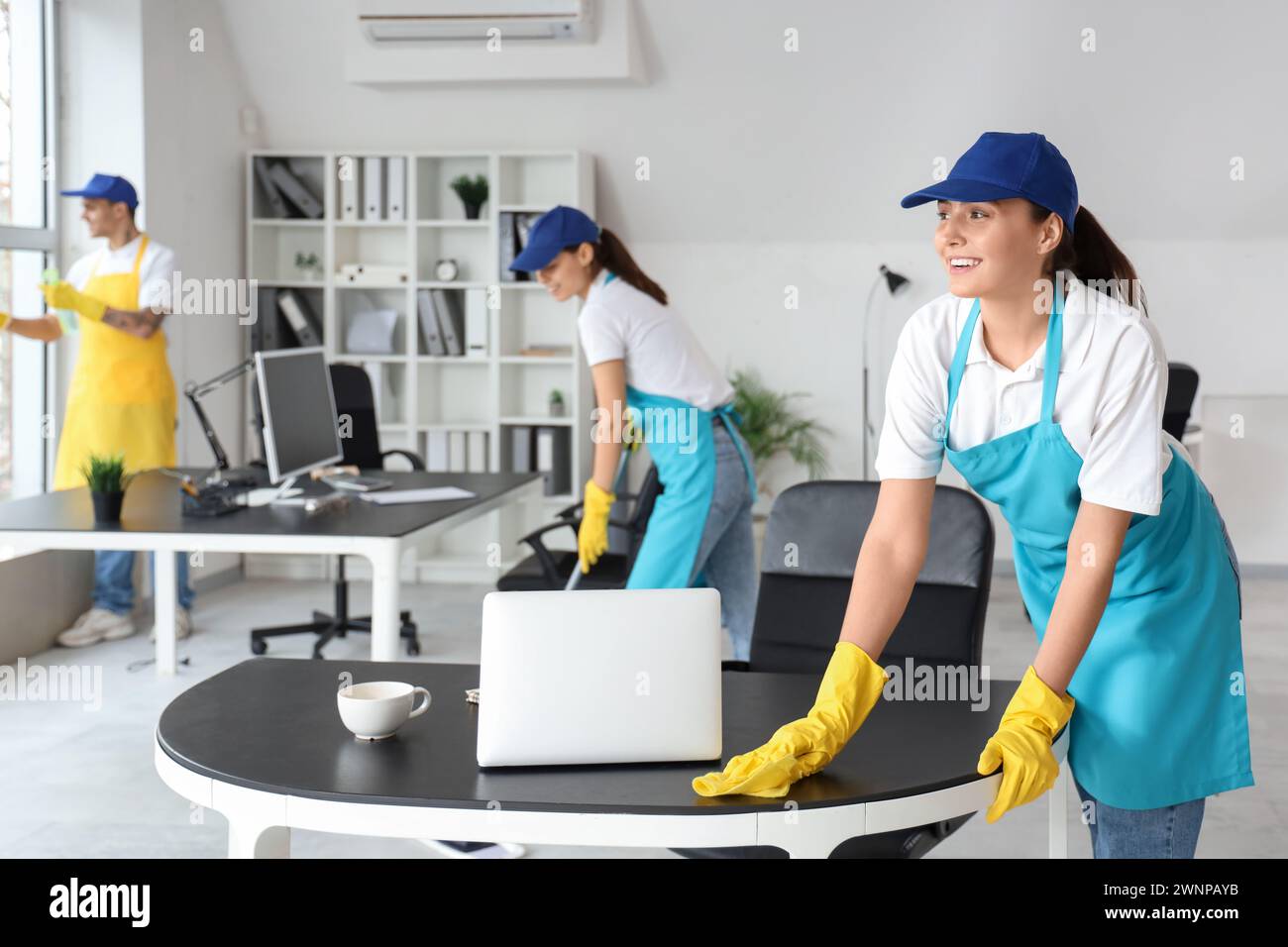 Female janitor cleaning table in office Stock Photo - Alamy