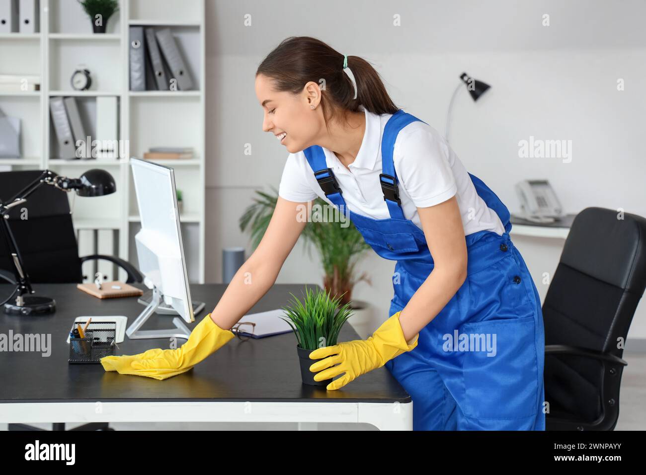 Female janitor cleaning table in office Stock Photo - Alamy