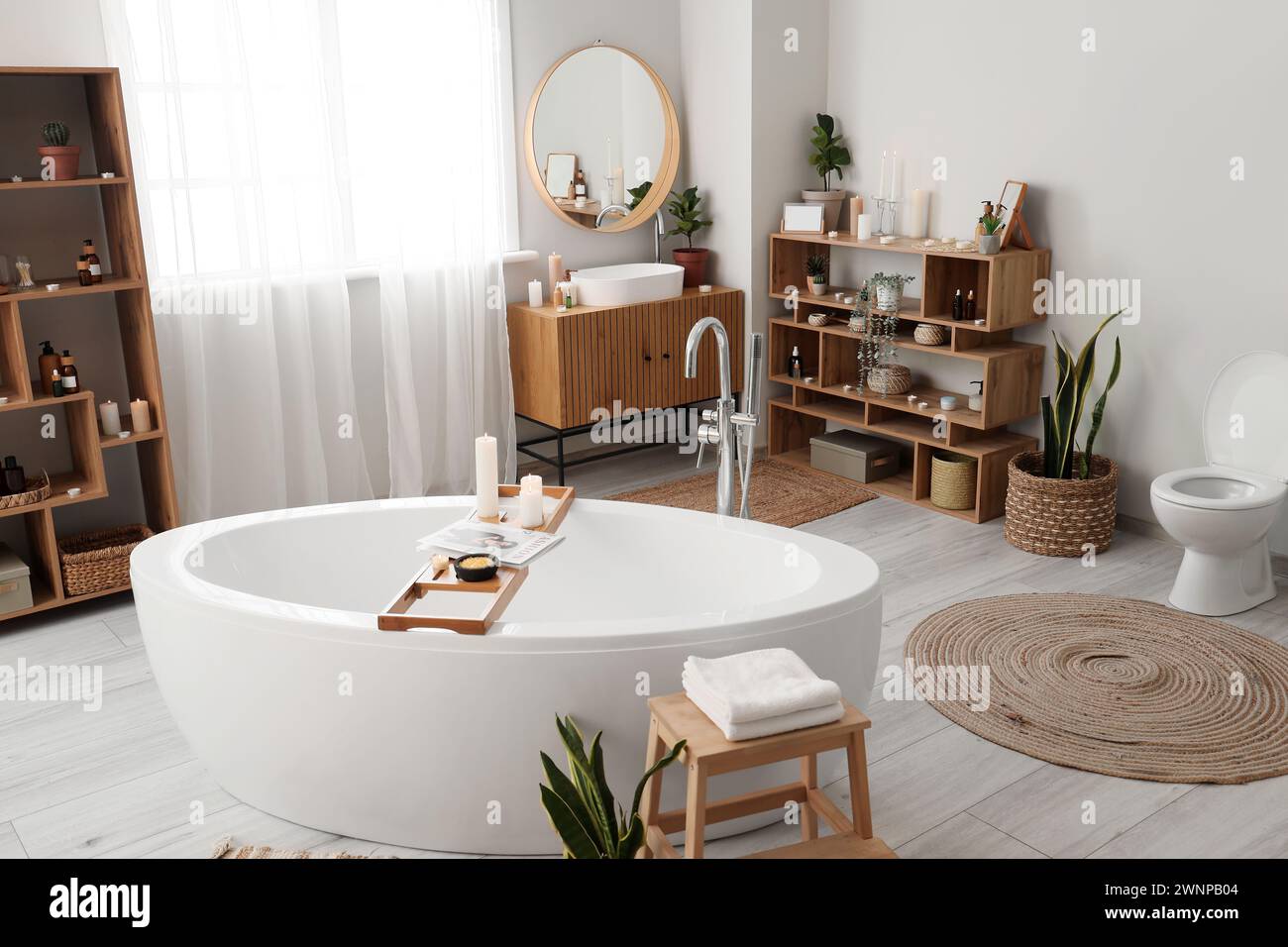 Interior of stylish bathroom with burning candles, bathtub and shelf ...