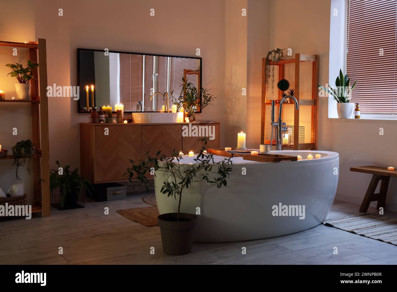 Interior of bathroom with burning candles, sink and bathtub in evening ...