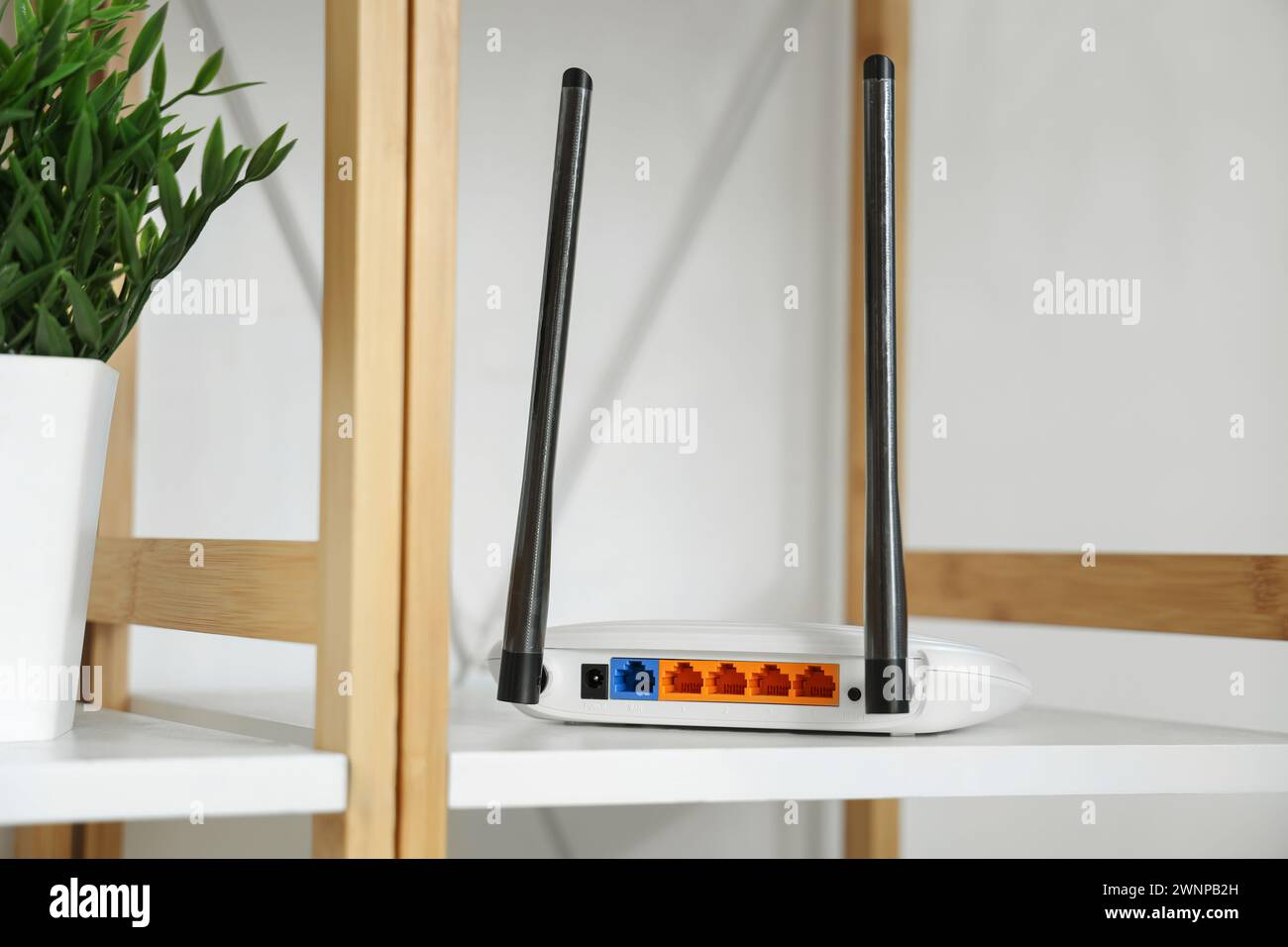 Modern wi-fi router on shelf near light wall, closeup Stock Photo - Alamy