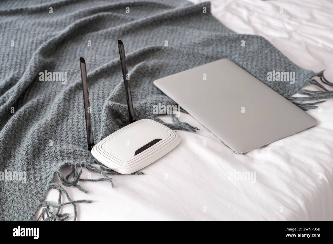 Modern wi-fi router with laptop on bed in room, closeup Stock Photo - Alamy