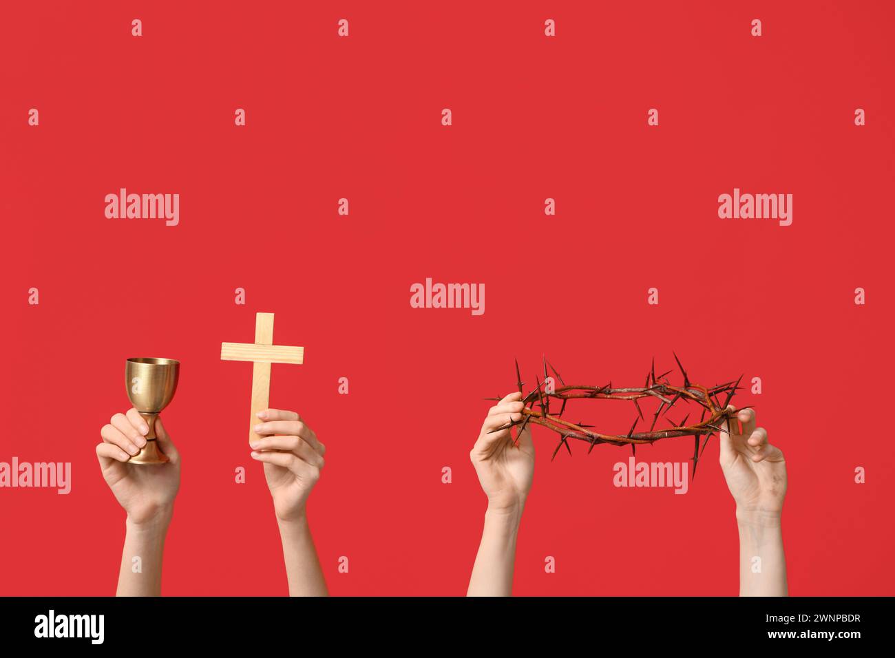 Female hands with crown of thorns, cup and cross on red background ...