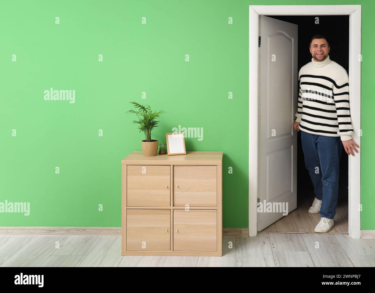 Young man walking through open door in room Stock Photo - Alamy