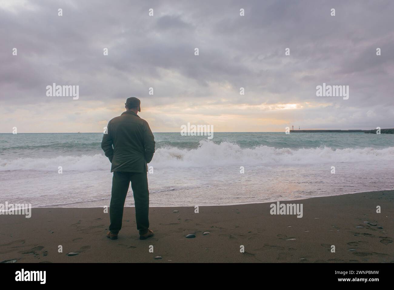 Solitary man standing by the seaside and staring in the distance. He's ...