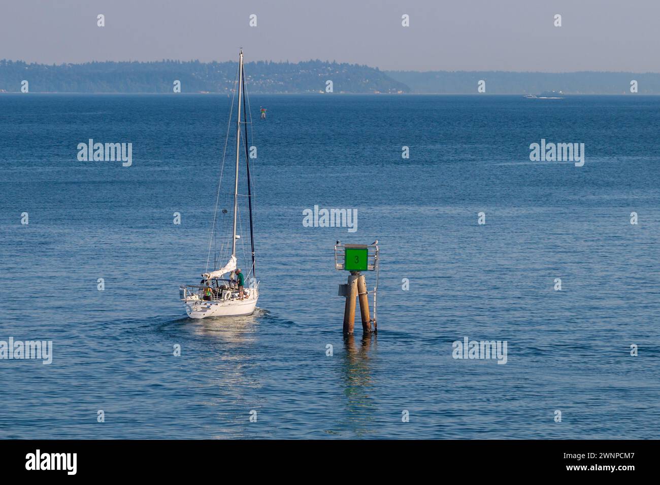 Sailboat under power makes a turn around a channel marker near ...