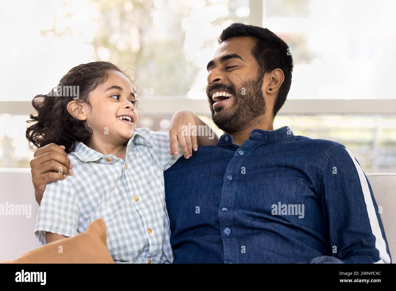 Cheerful caring young Indian dad hugging happy little daughter kid ...