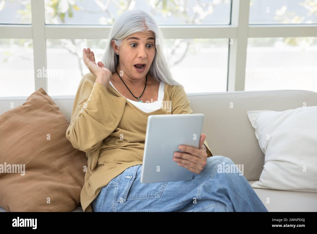 Excited elderly woman staring at tablet screen Stock Photo - Alamy