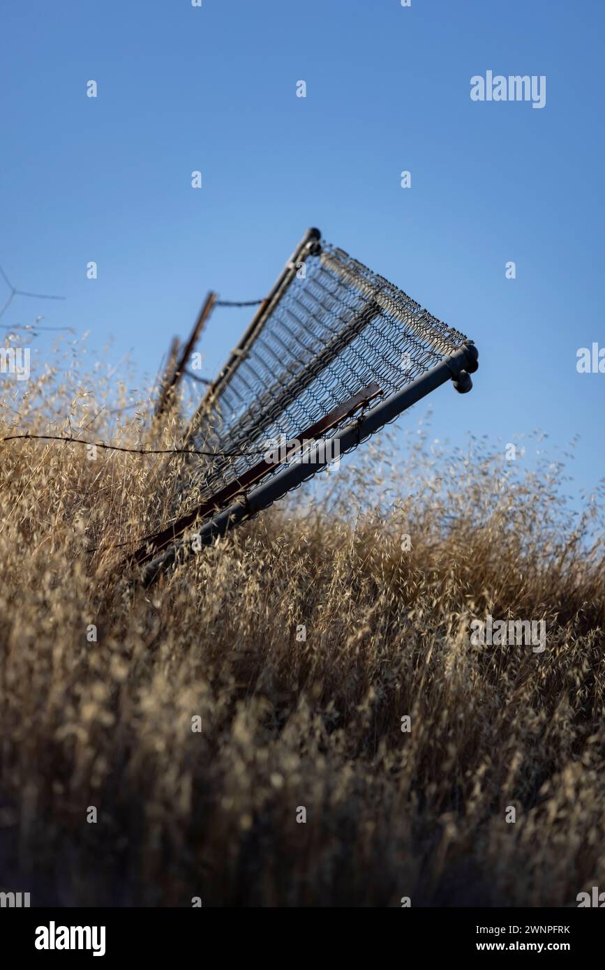 A chain lin fence is falling over along a hillside in the hills of the ...