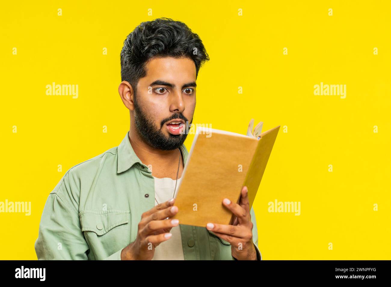 Happy relaxed smiling Indian young man reading funny interesting ...