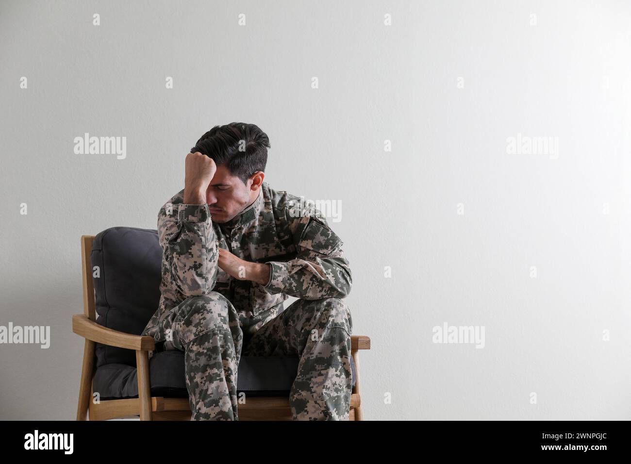 Stressed military officer sitting in armchair on white background ...