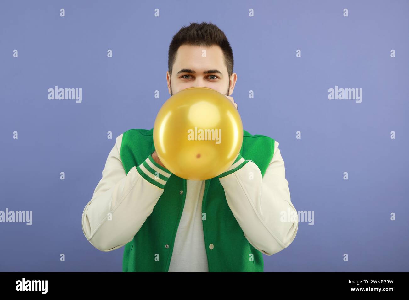 Man inflating bright balloon on violet background Stock Photo - Alamy
