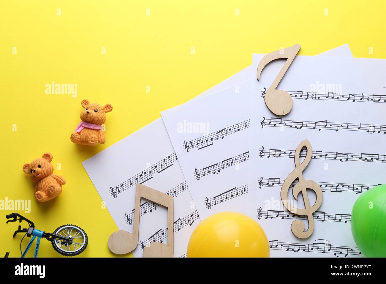 Baby songs. Music sheets, wooden notes and different toys on yellow ...