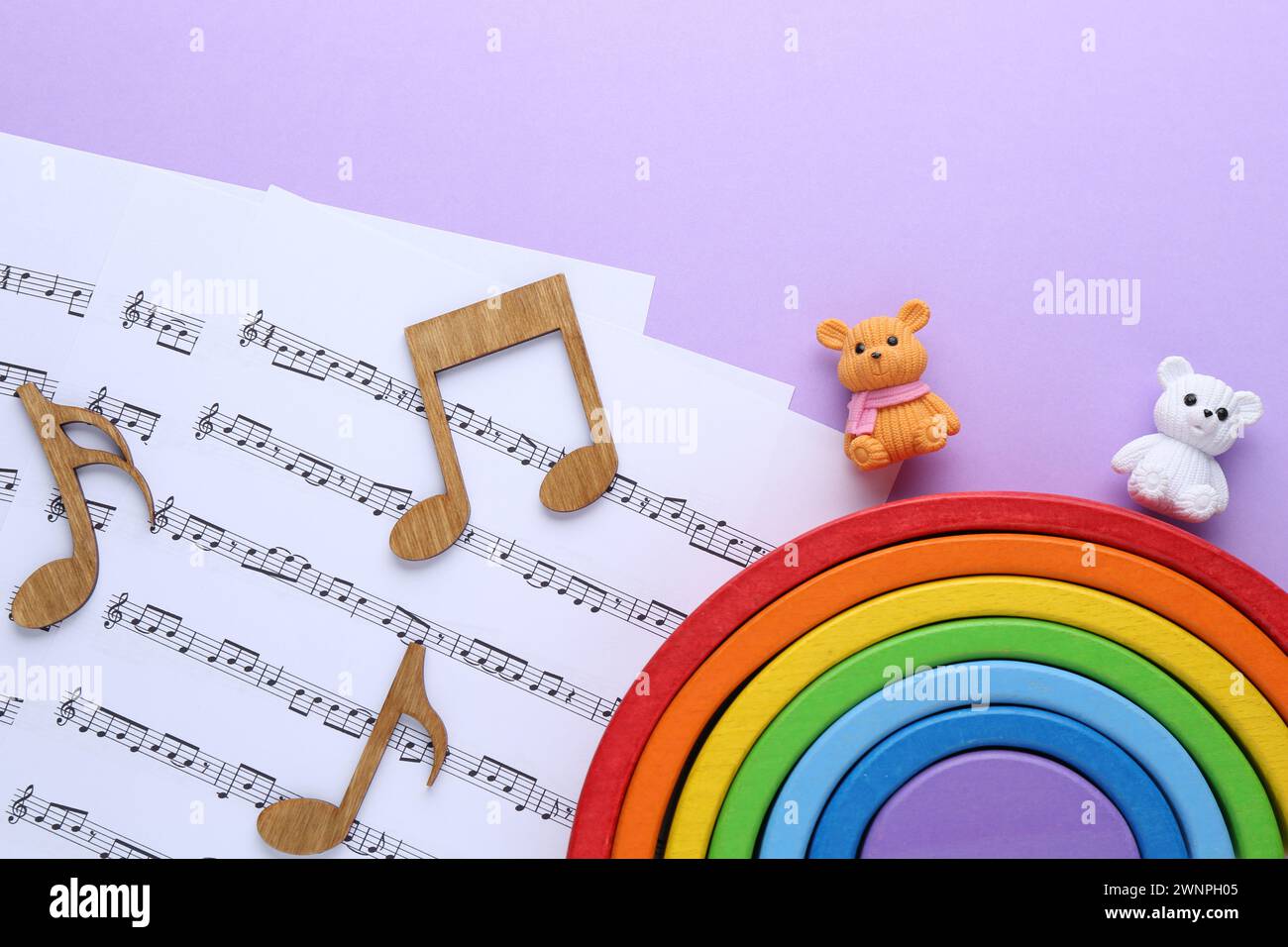 Wooden notes, music sheets and toys on violet background, top view ...