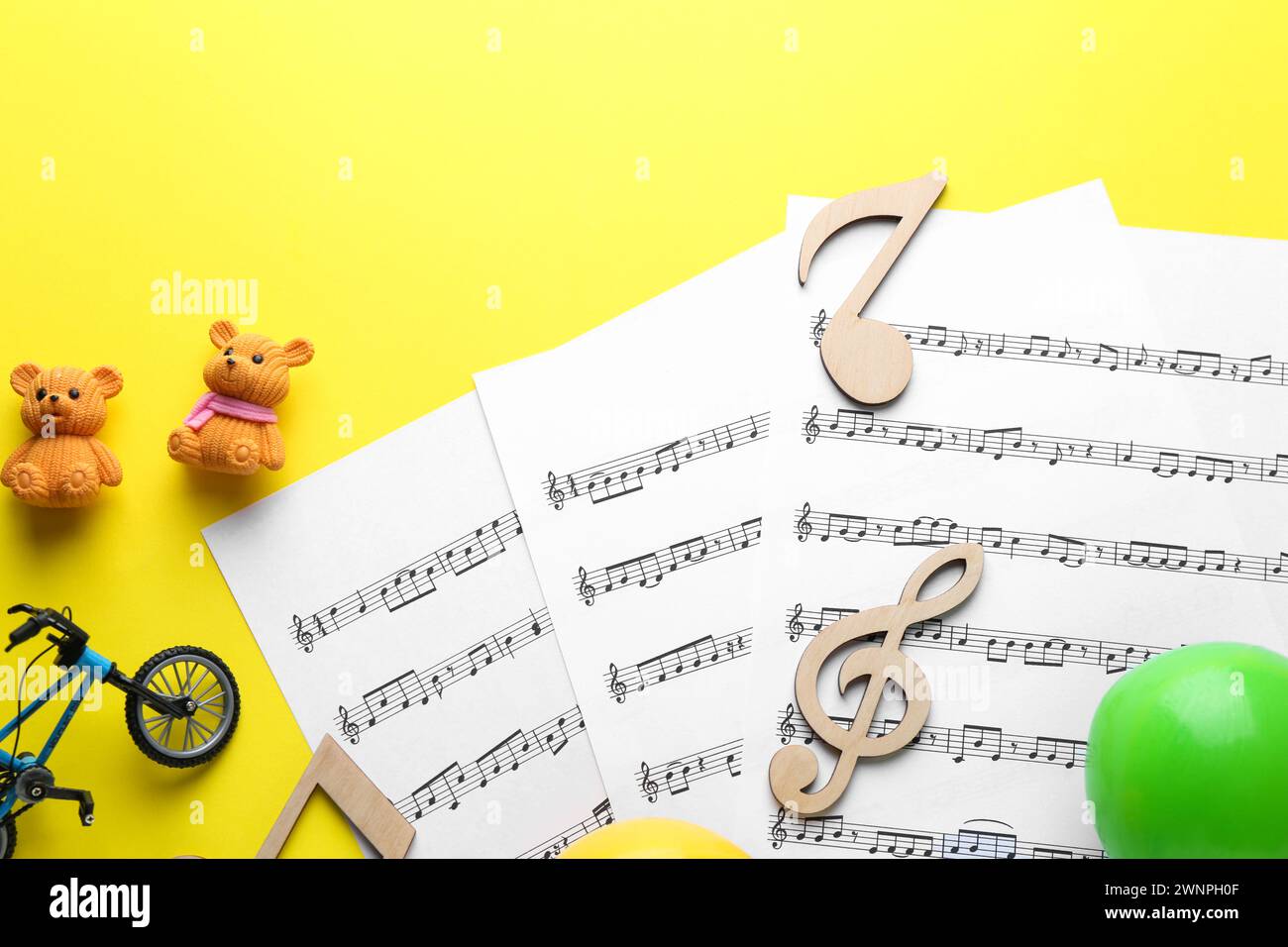 Baby songs. Music sheets, wooden notes and different toys on yellow ...