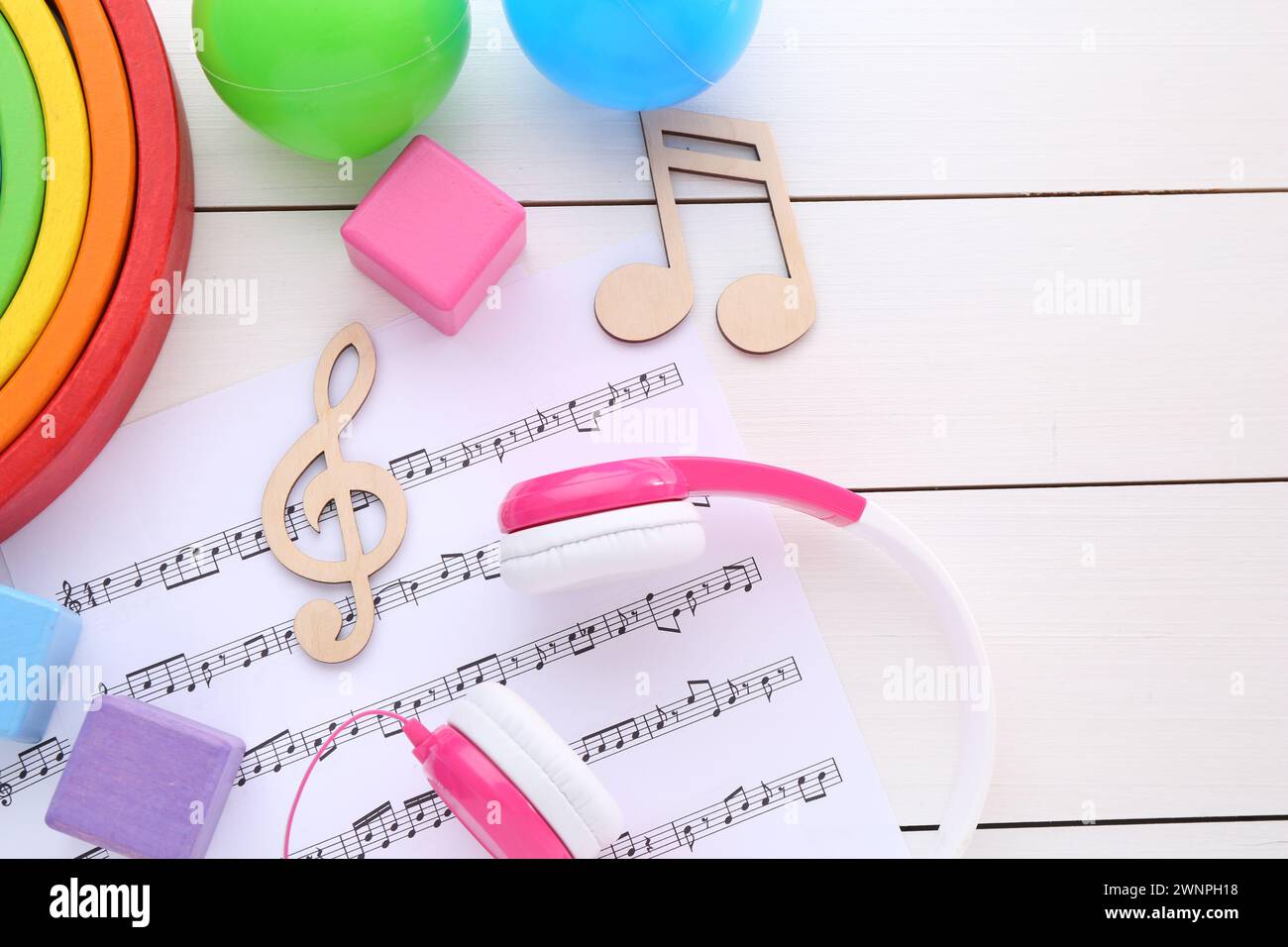 Notes, music sheet, headphones and toys on white wooden table, flat lay ...