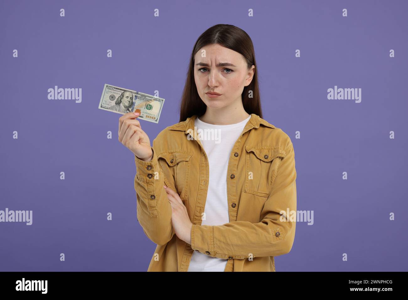 Sad woman with dollar banknote on purple background Stock Photo - Alamy