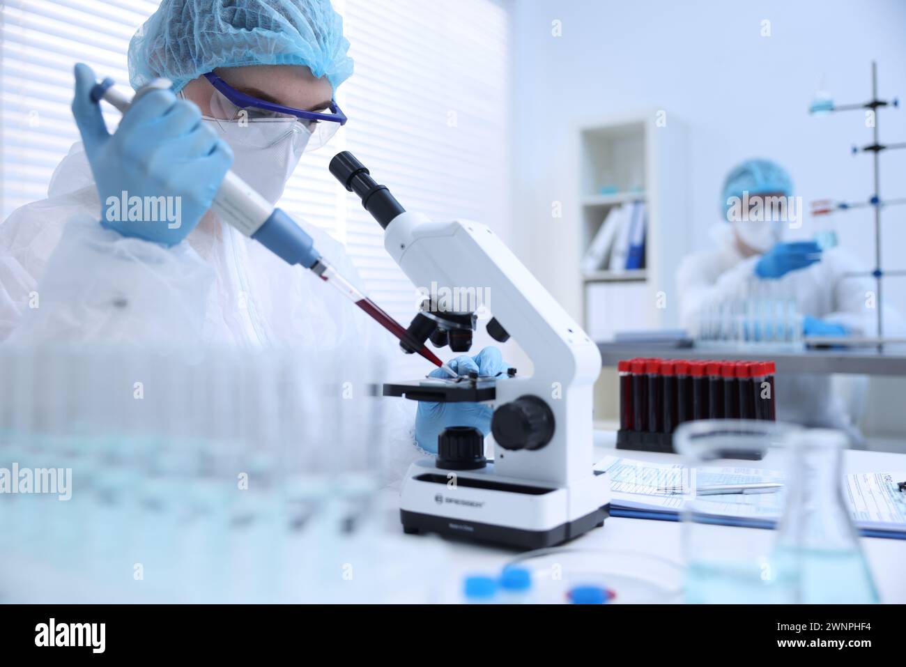 Scientist dripping sample onto glass slide while working with ...