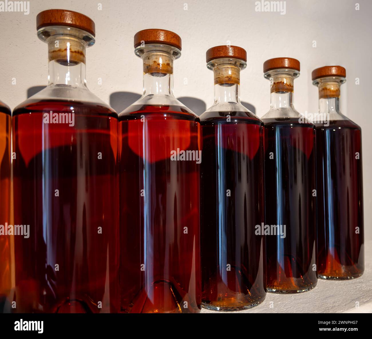 Different colours and ages of cognac spirits in bottles in distillery ...