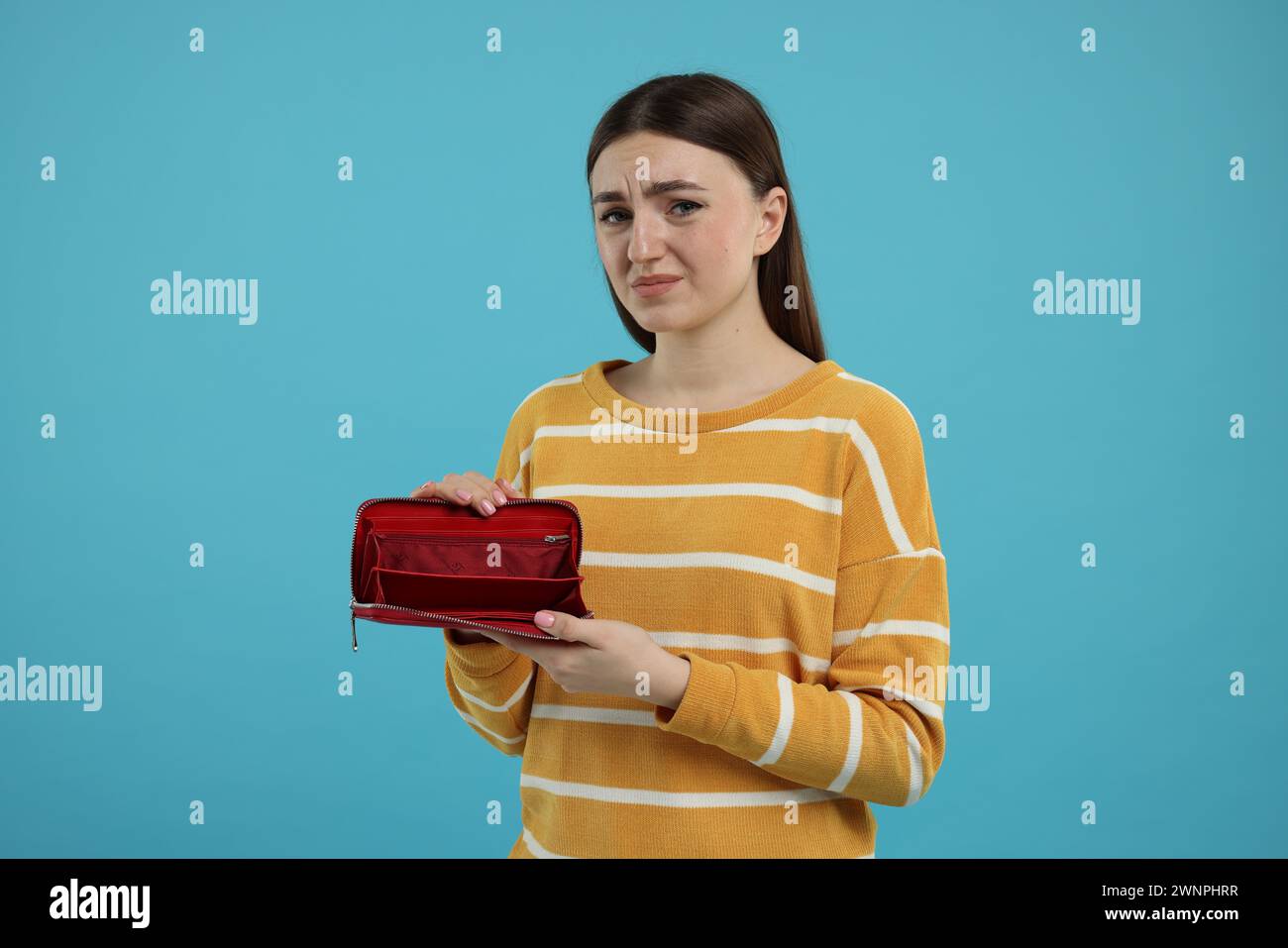 Sad woman showing empty wallet on light blue background Stock Photo - Alamy