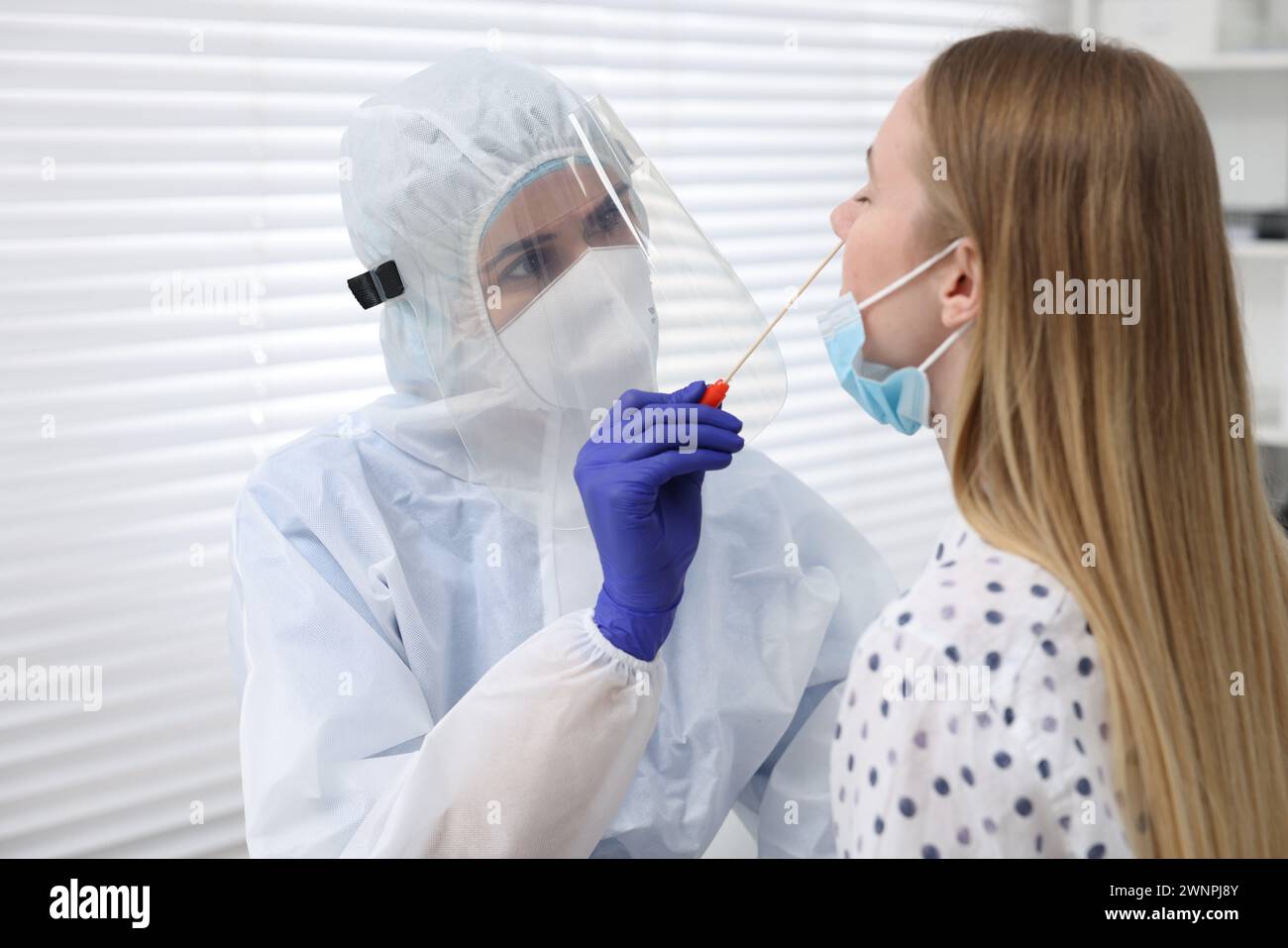 Laboratory testing. Doctor in uniform taking sample from patient's nose ...