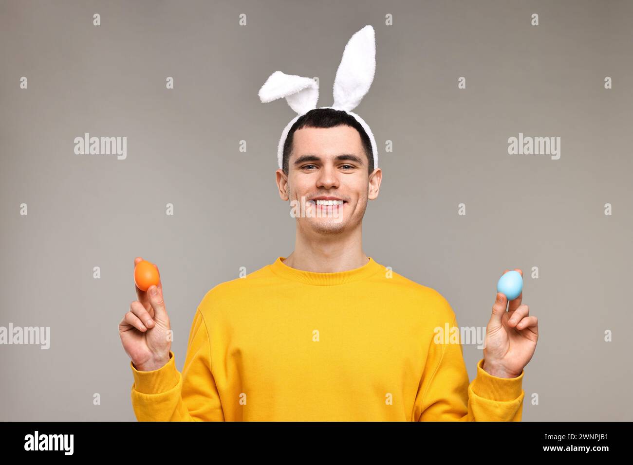 Easter celebration. Handsome young man with bunny ears holding painted ...