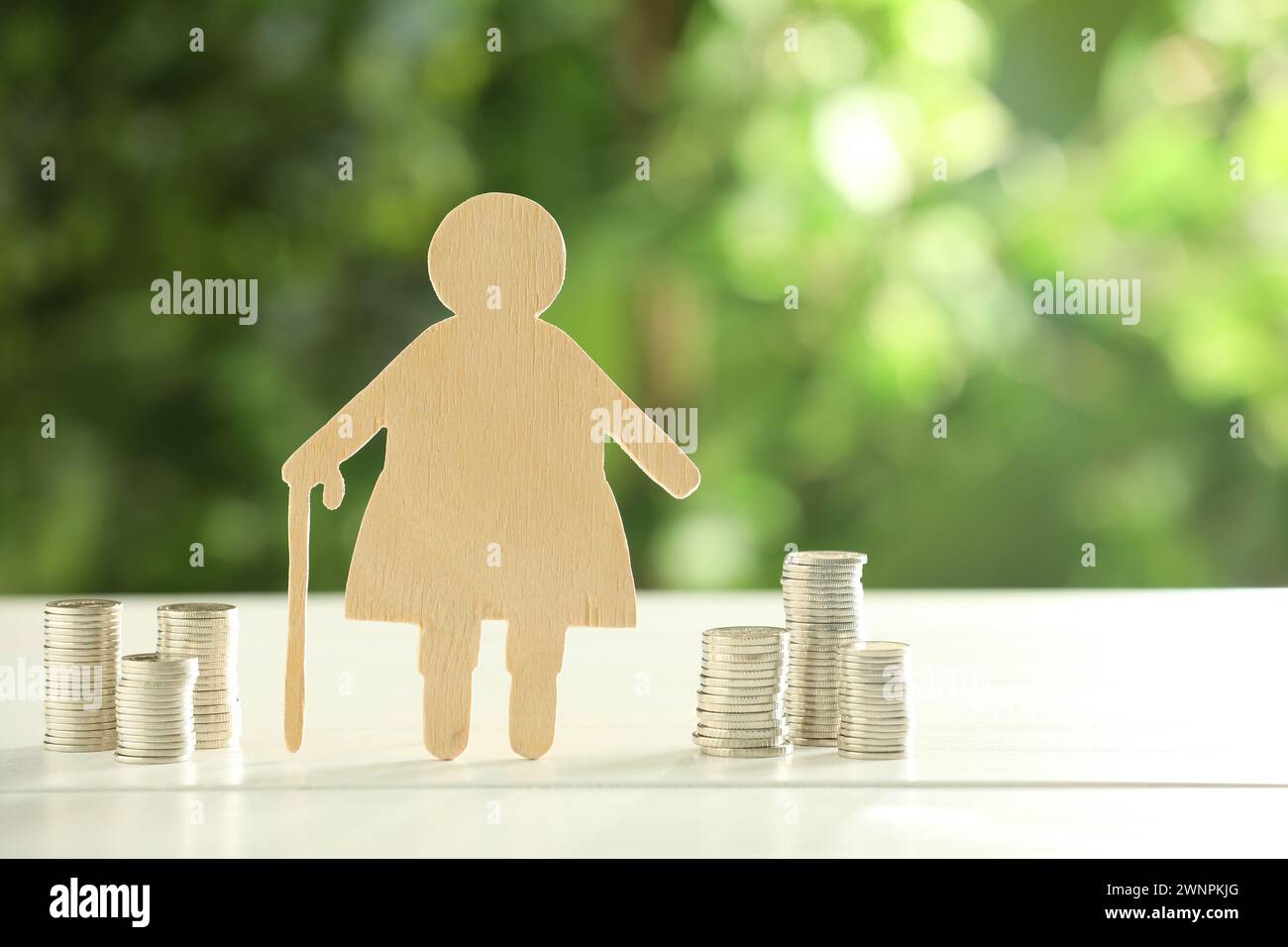 Pension savings. Figure of senior woman and stacked coins on white ...