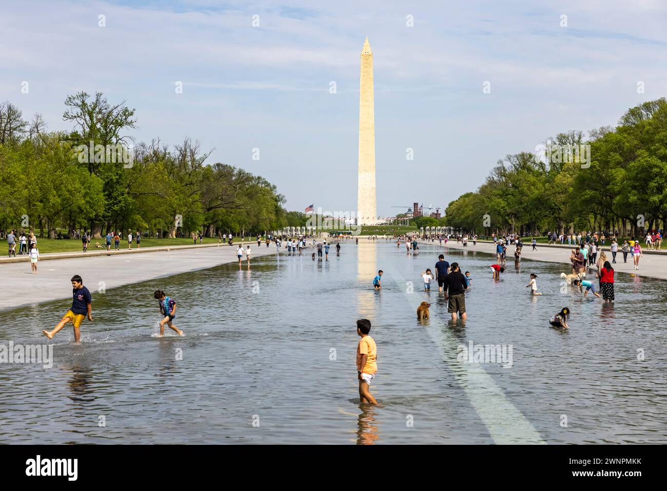 People in the reflecting pool in Washington, DC on a warm day with a ...