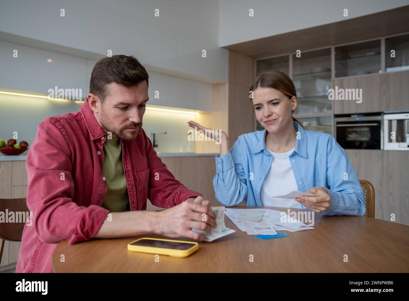 Upset married couple calculates expenses while sorting through receipts ...