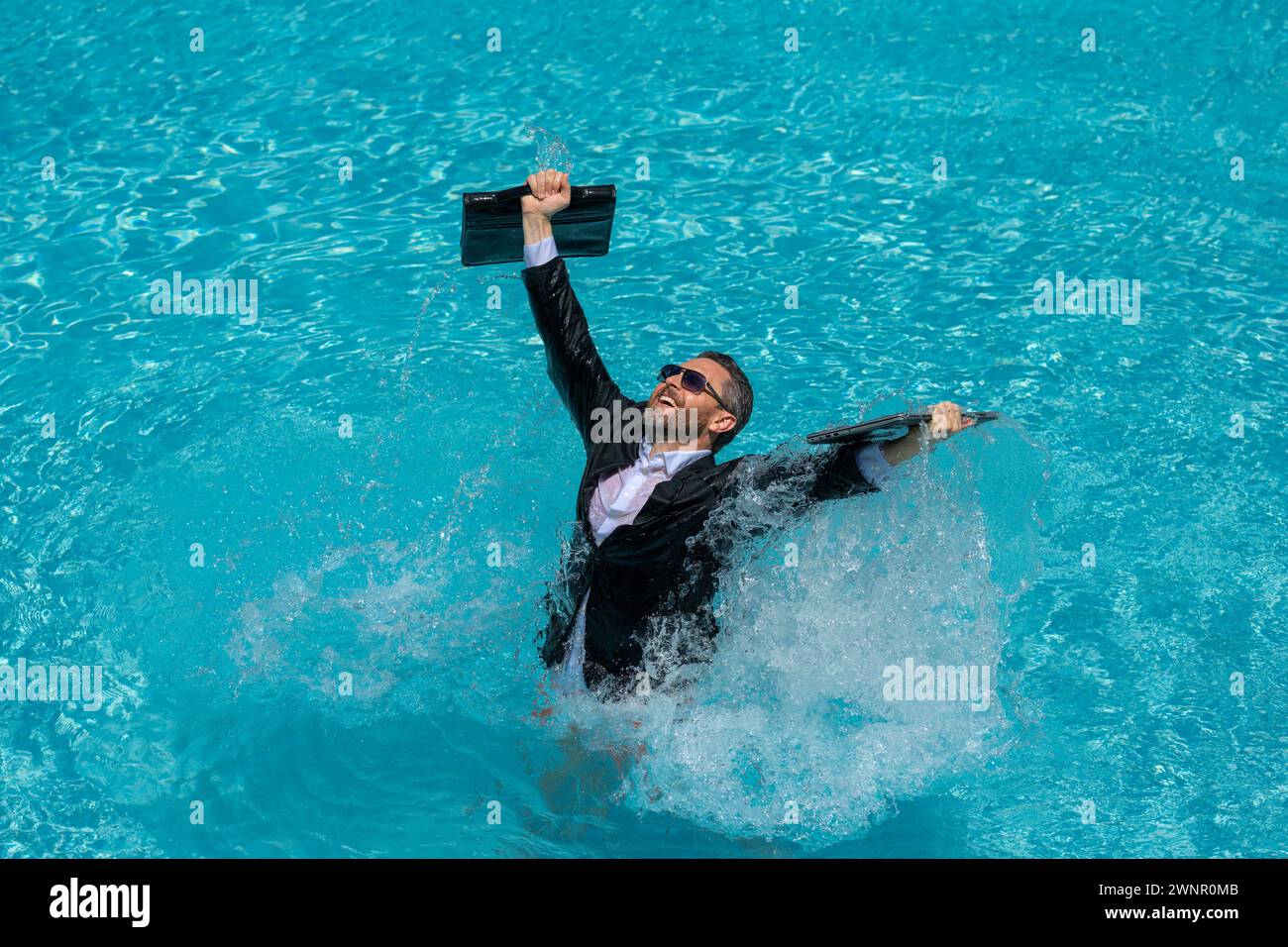 Business man in suit and laptop splash water in swimming pool. Crazy ...