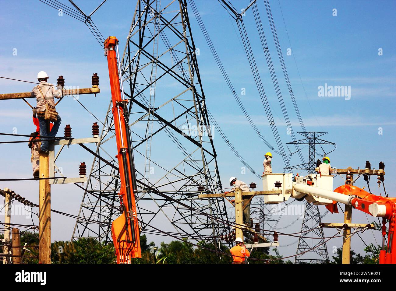group of electric worker working on pole connected high voltage wires ...