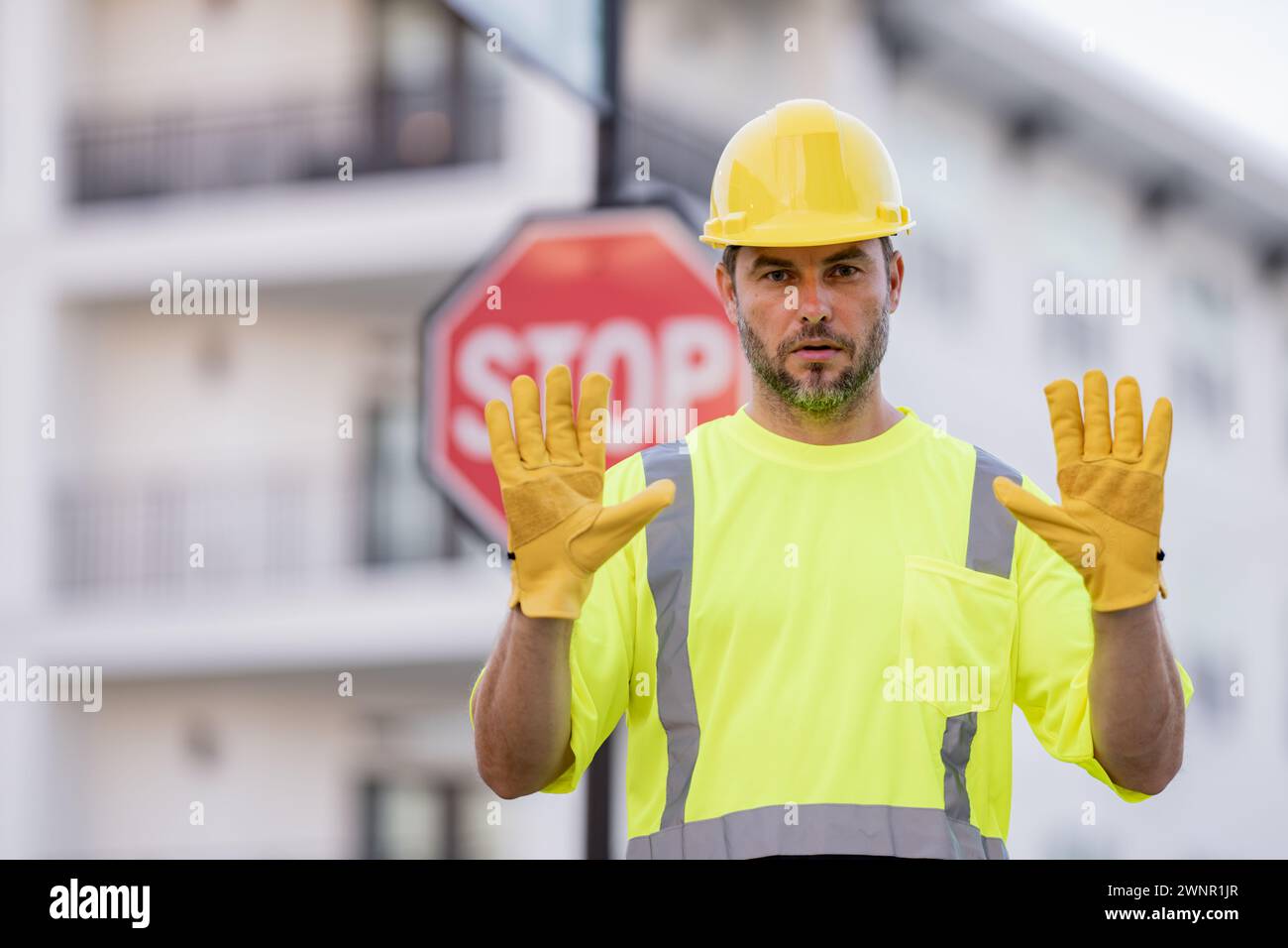 Worker in uniform gesturing stop. Builder with stop road sign. Builder ...