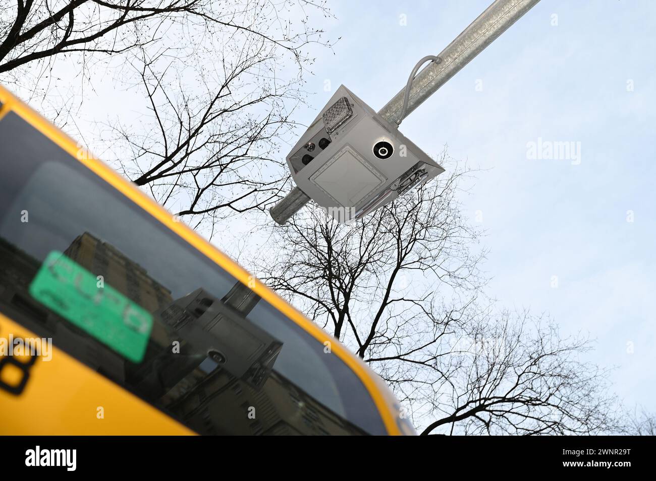 A yellow taxi passes under a gantry supporting a license plate and E-Z ...