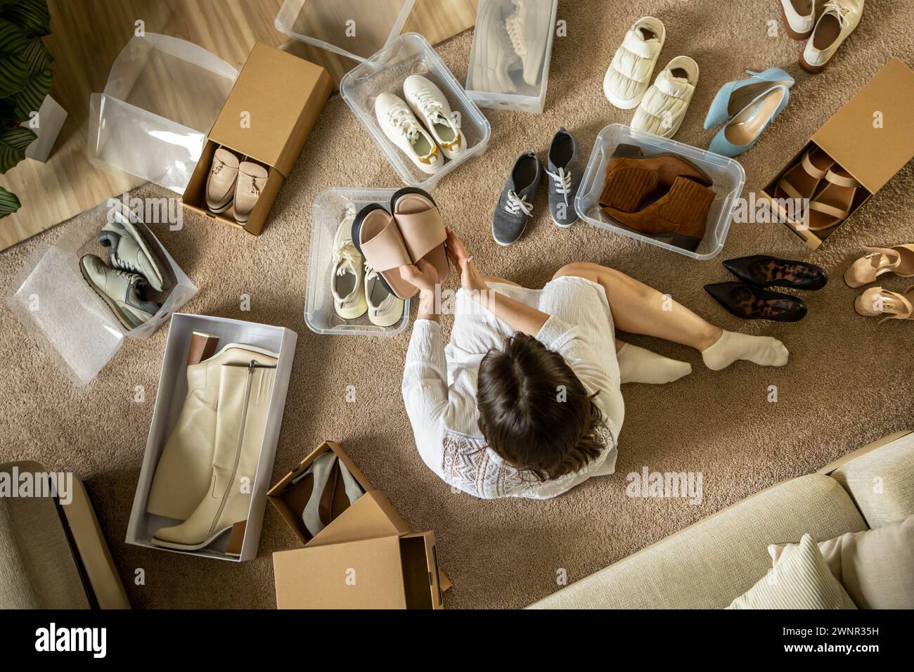 Woman packing shoes into PVC container and cardboard box tidying up ...