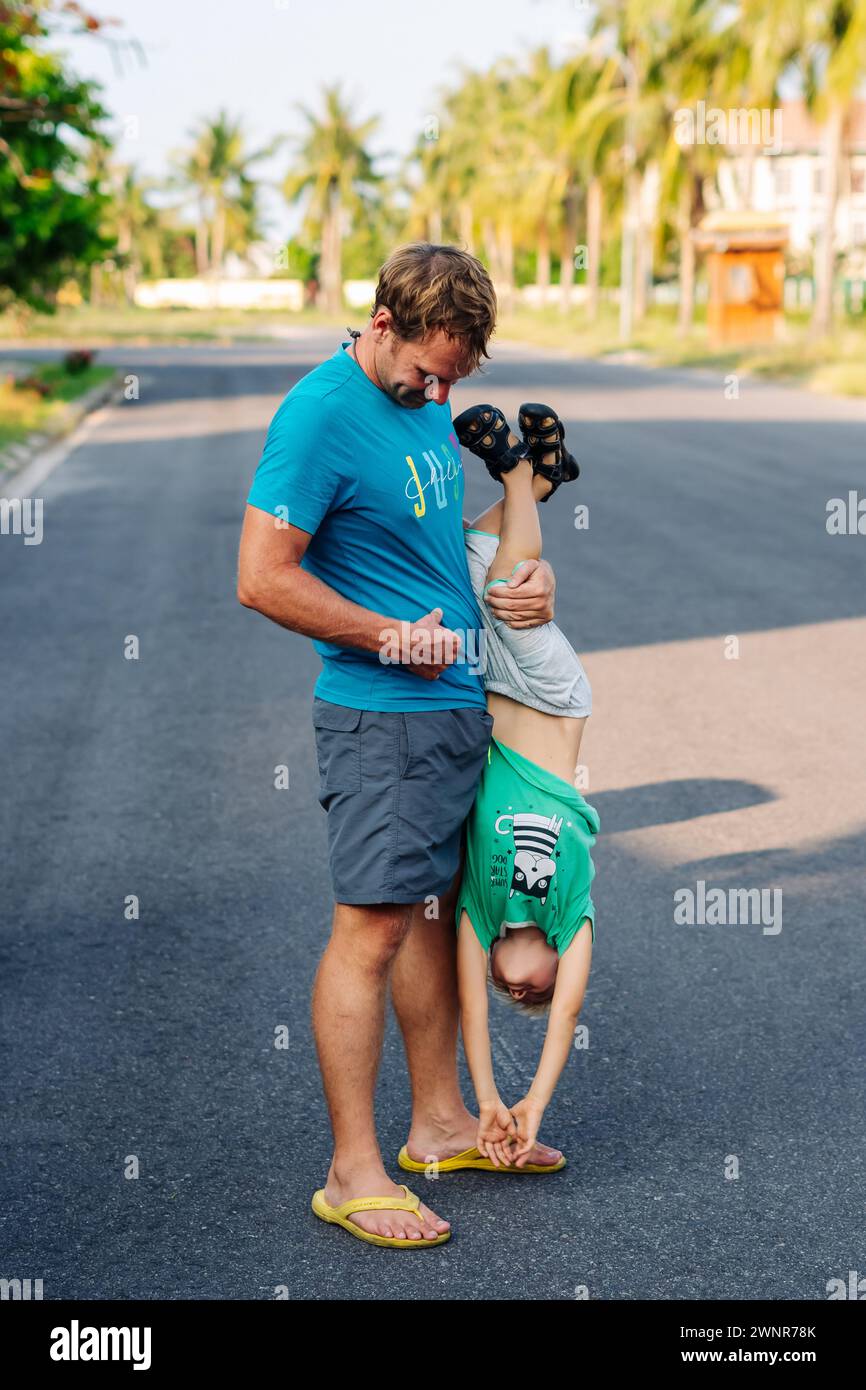 Father son have fun. Man holds child's leg upside down head. Joy ...