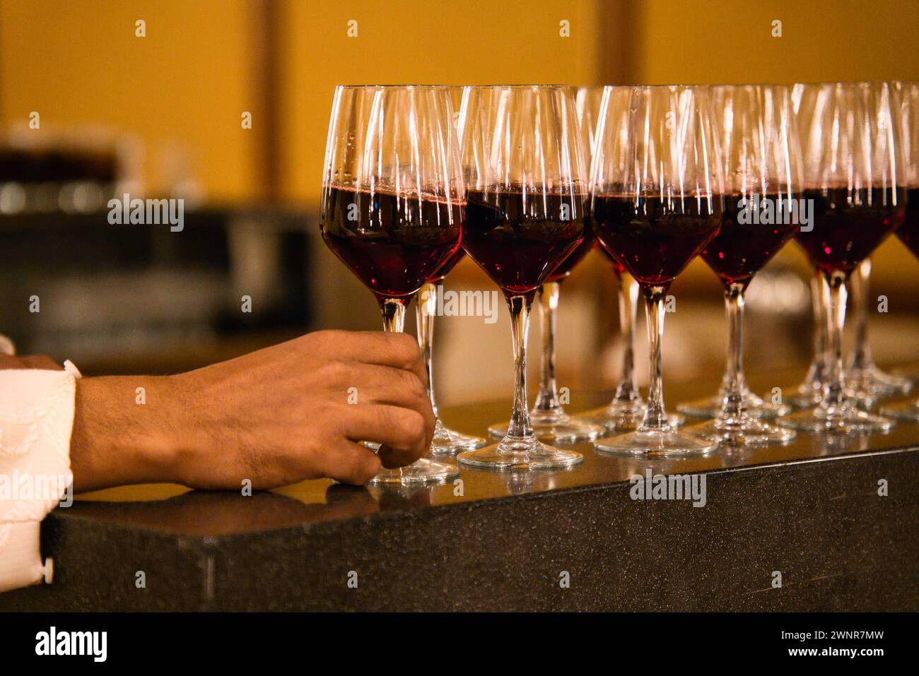 Hand reaching for row of wine glasses. Waiter preparing wine glasses on ...