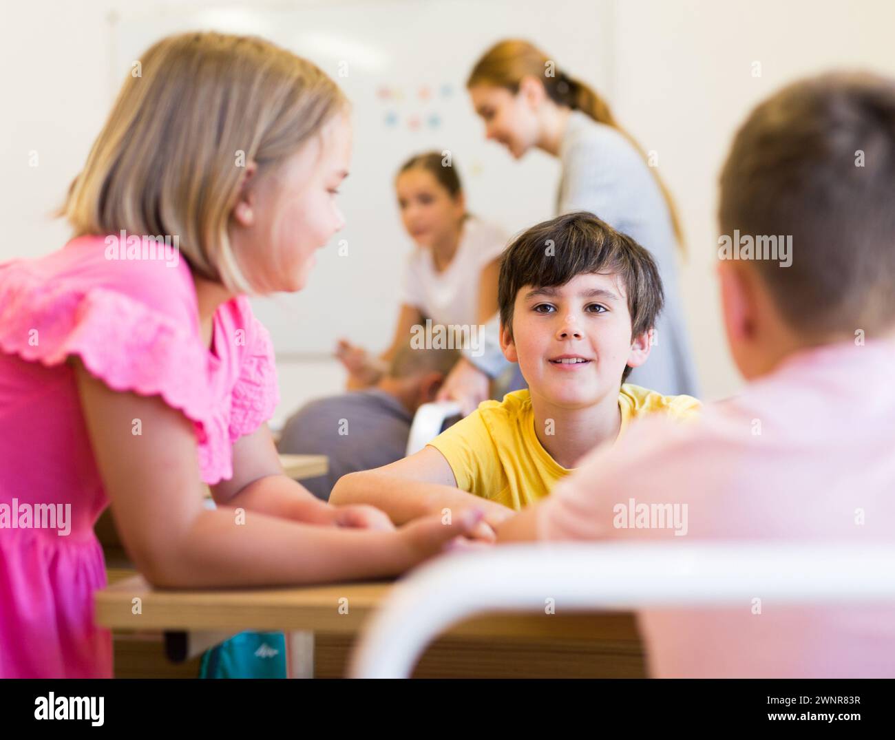 Interested tween boy discussing teacher assignment with classmates ...