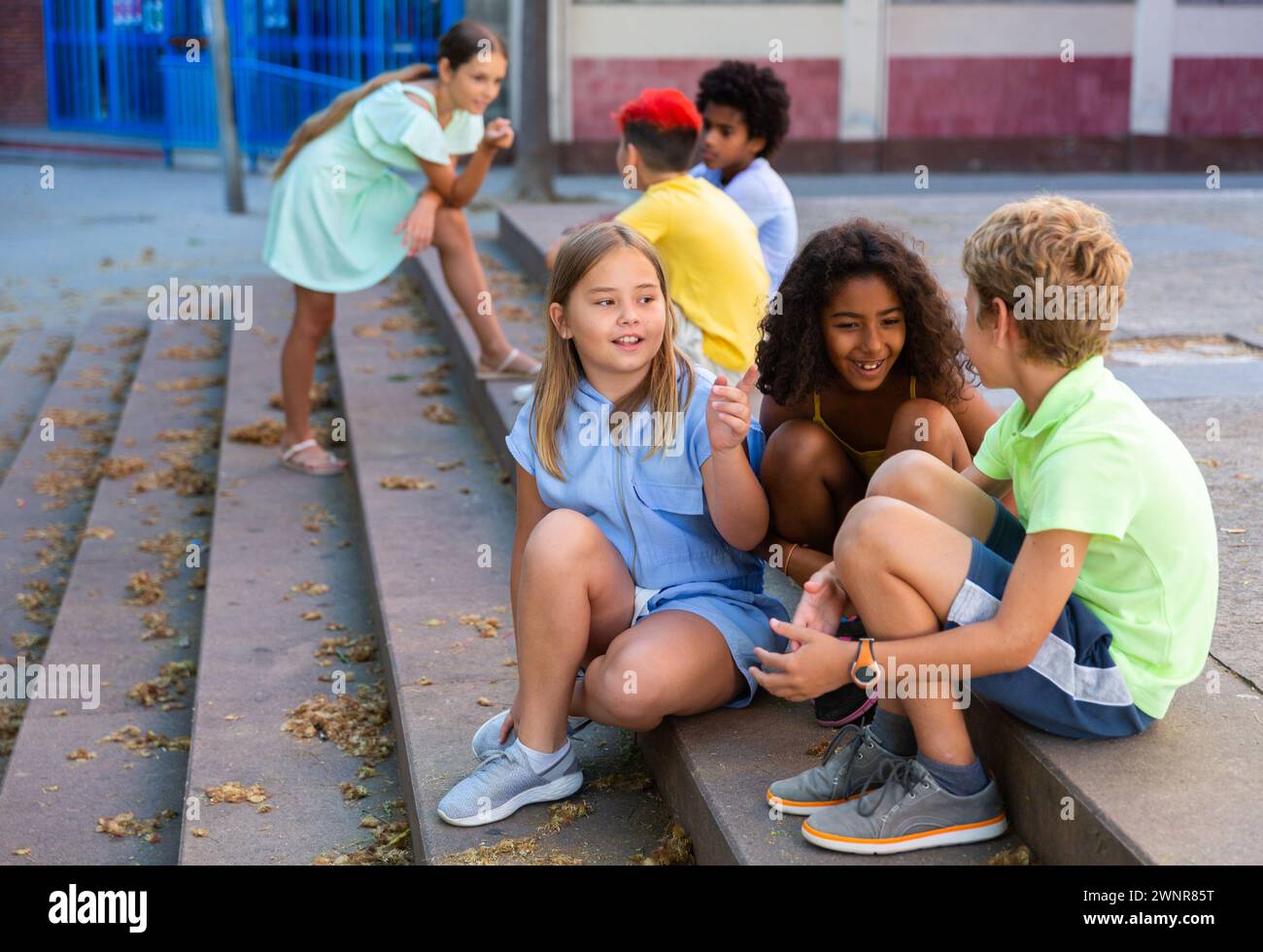 Children talking together while sitting on stairs outdoors Stock Photo ...