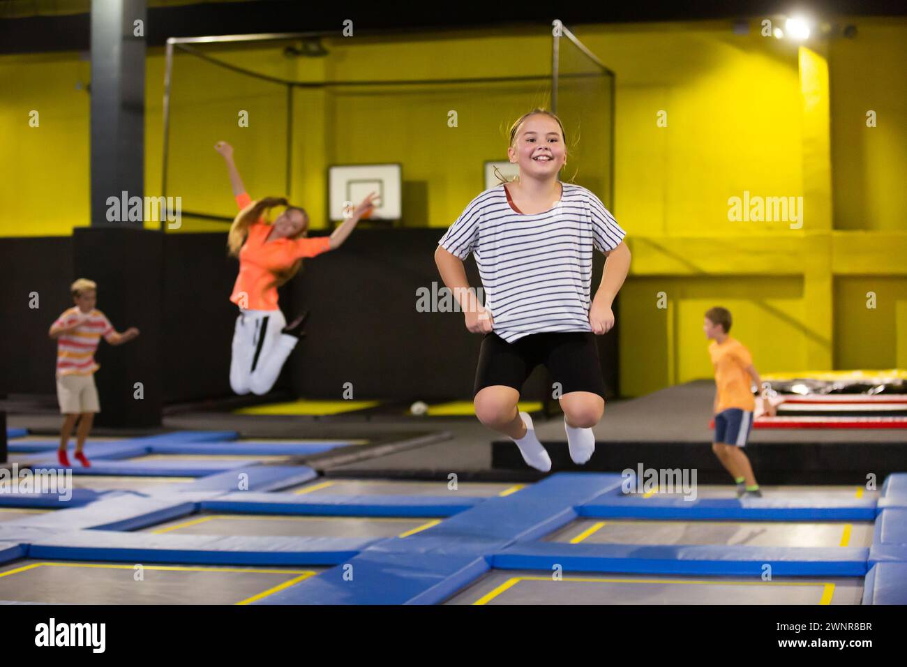 Tween girl bouncing on trampoline in indoor amusement park Stock Photo ...